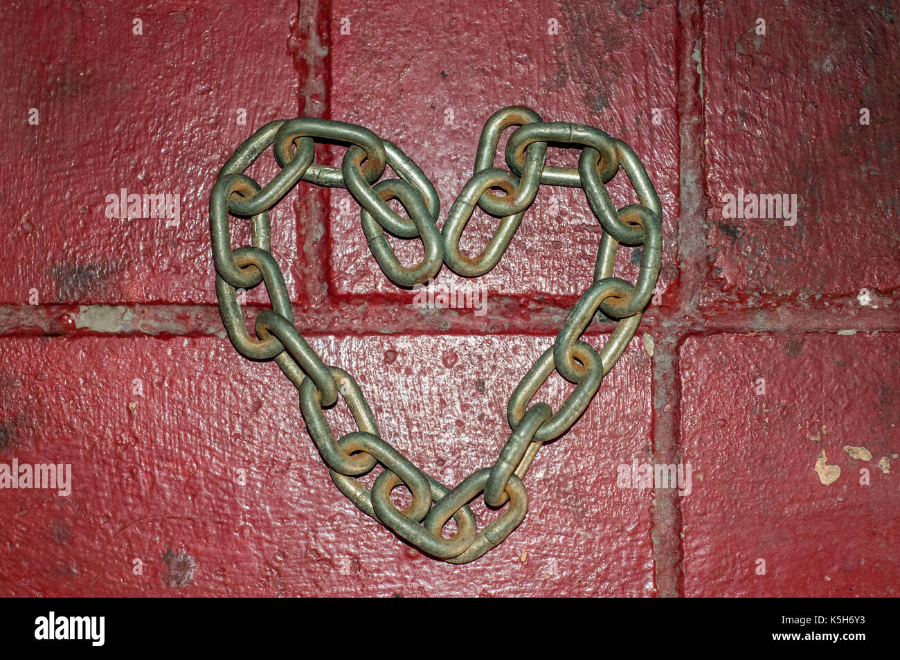 Heart-shaped chain on a red brick wall Stock Photo - Alamy