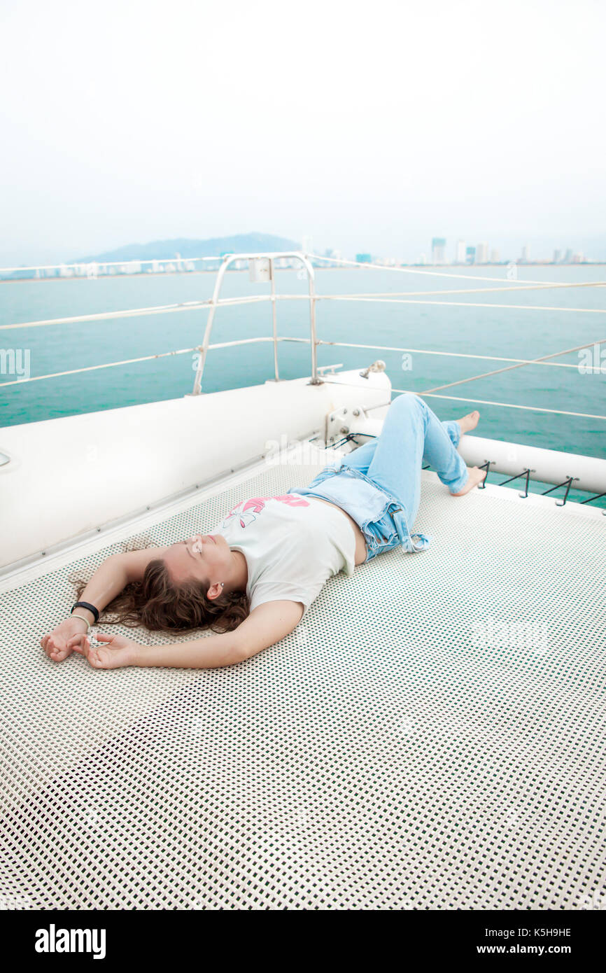Young woman resting on ship deck while enjoying a cruise on a boat ...