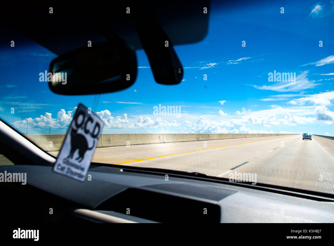 View of freeway from interior of car with sign hanging from rear view ...