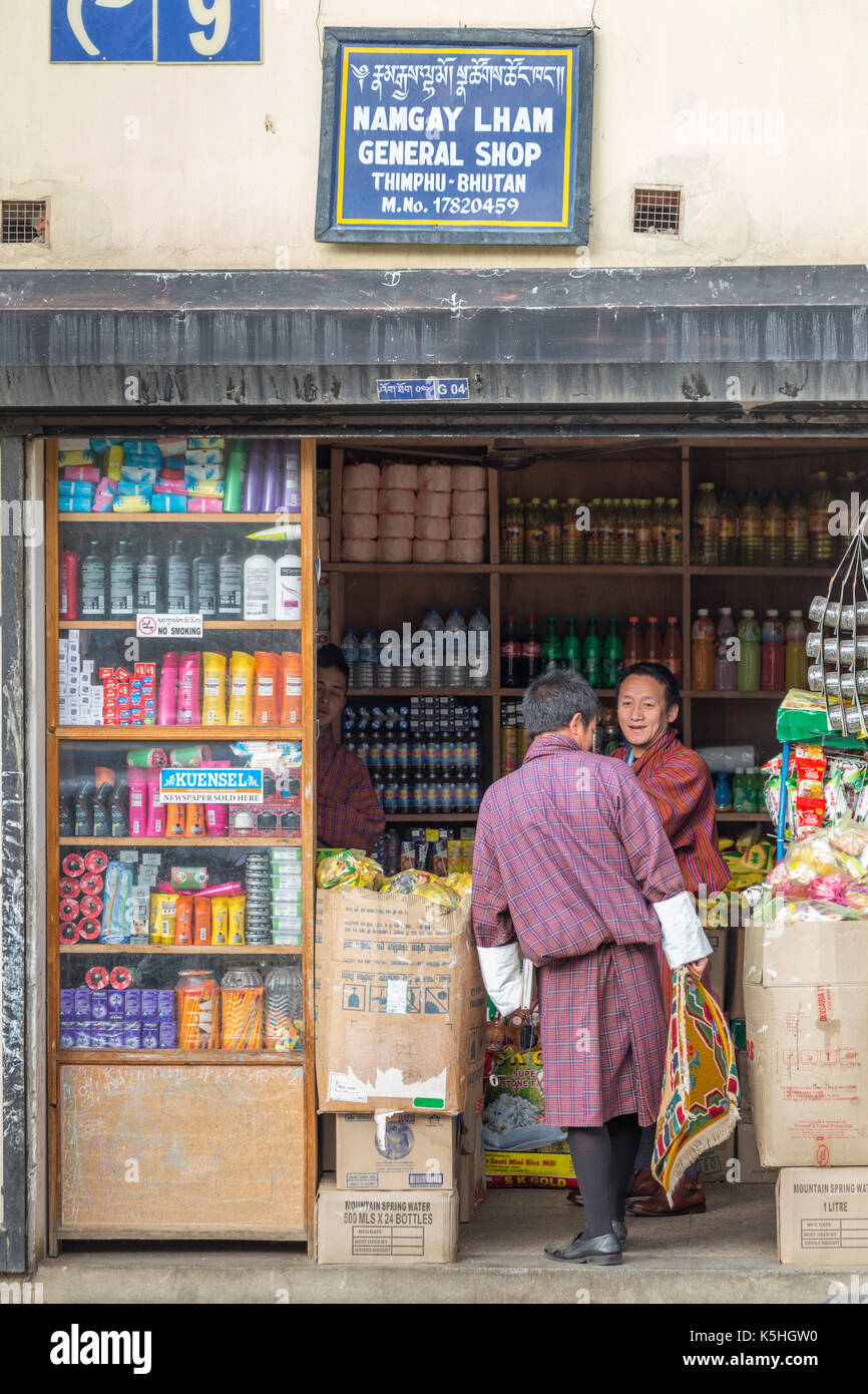 Two Thimphu citizens in traditional costume in Namgay Lham General Shop ...
