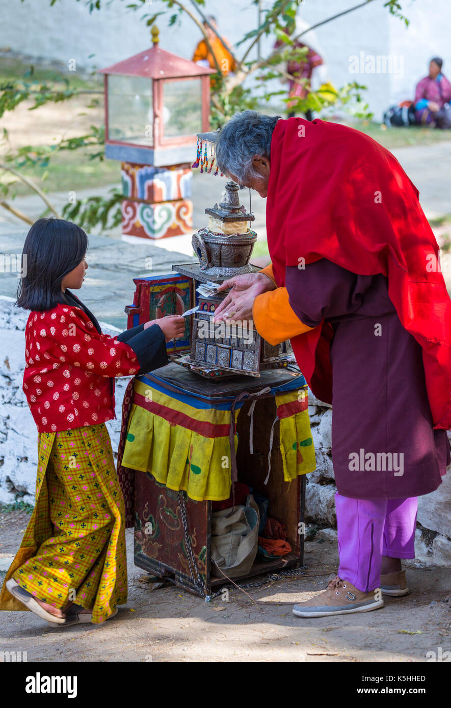 Young girl making a donation to a monk outside Punakha Dzong, Western ...