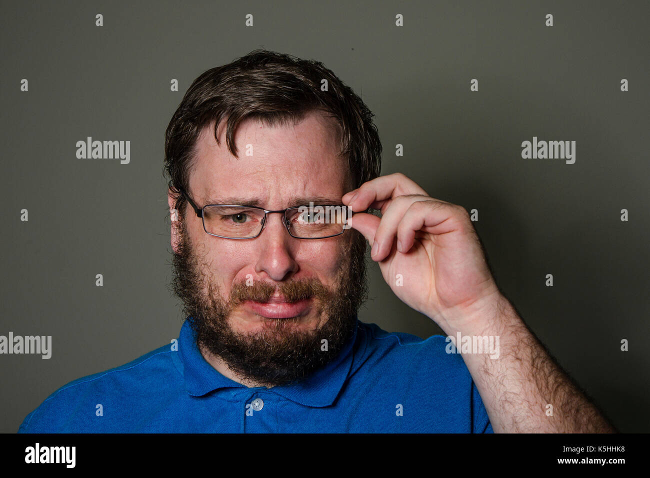 Man removing his glasses while crying Stock Photo - Alamy