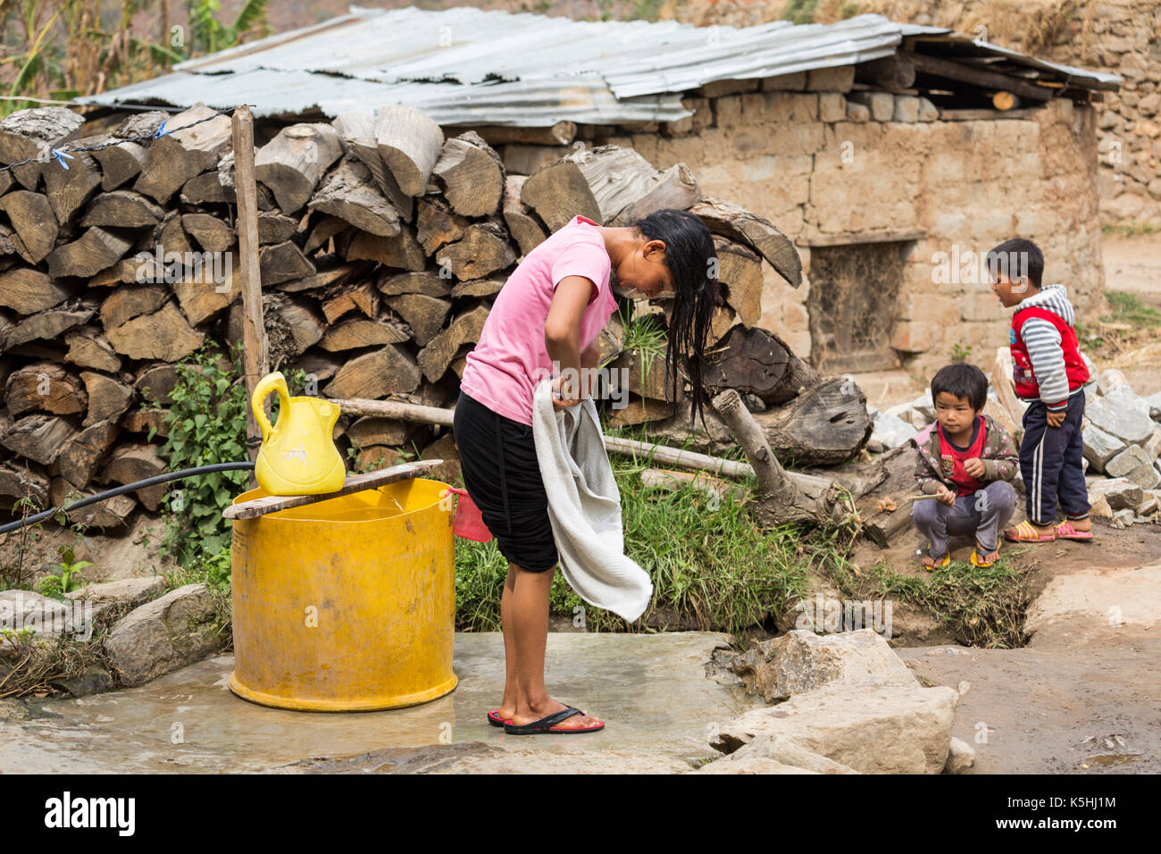 Young woman washing outside her house in Lobesa, Punakha, Western ...