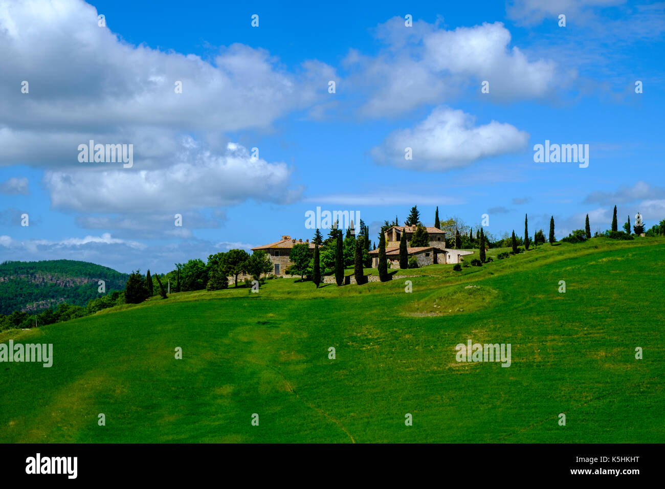 Typical tuscanian landscape with a farmhouse on a hill, cypresses ...