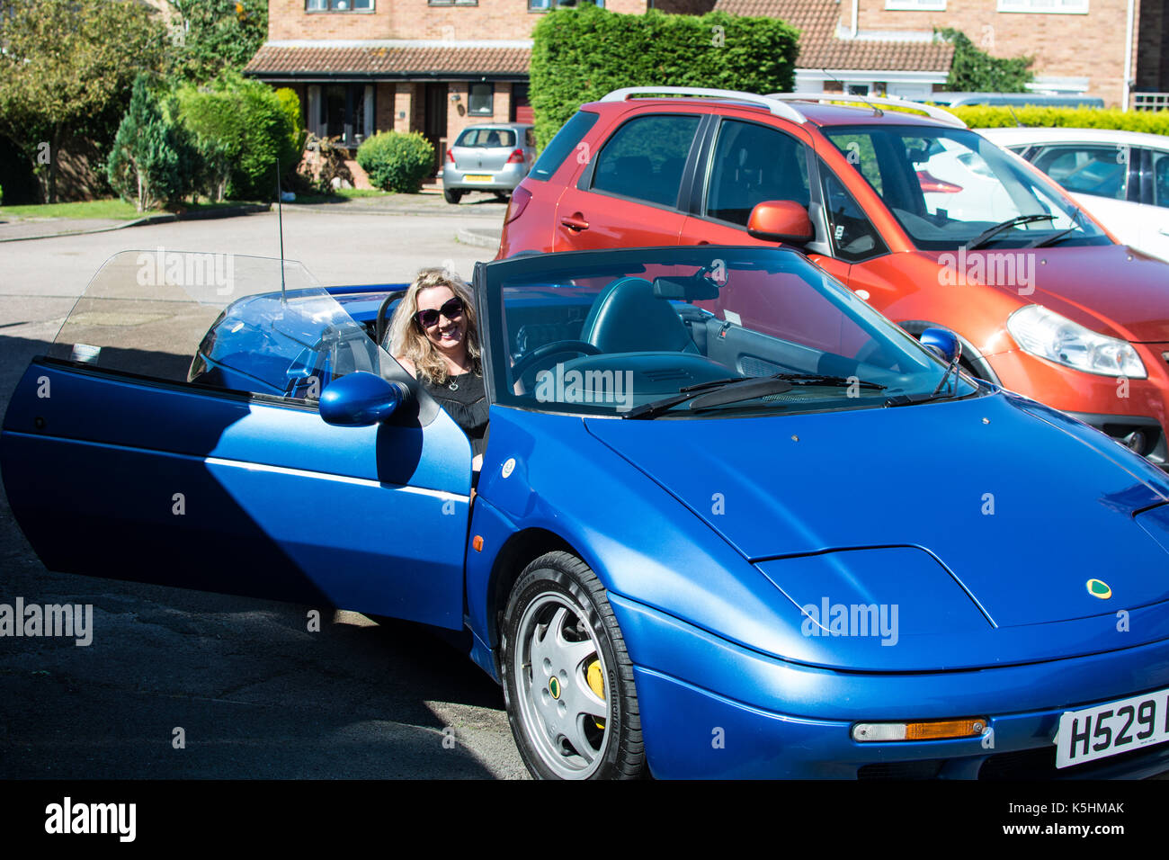 Blonde girl in a Lotus Elan M100 sports car happy smiling long hair ...