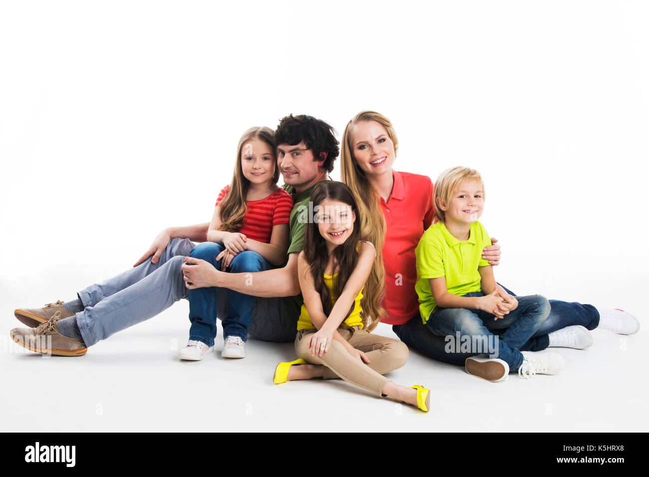 Portrait of happy family with three children sitting on the floor at ...