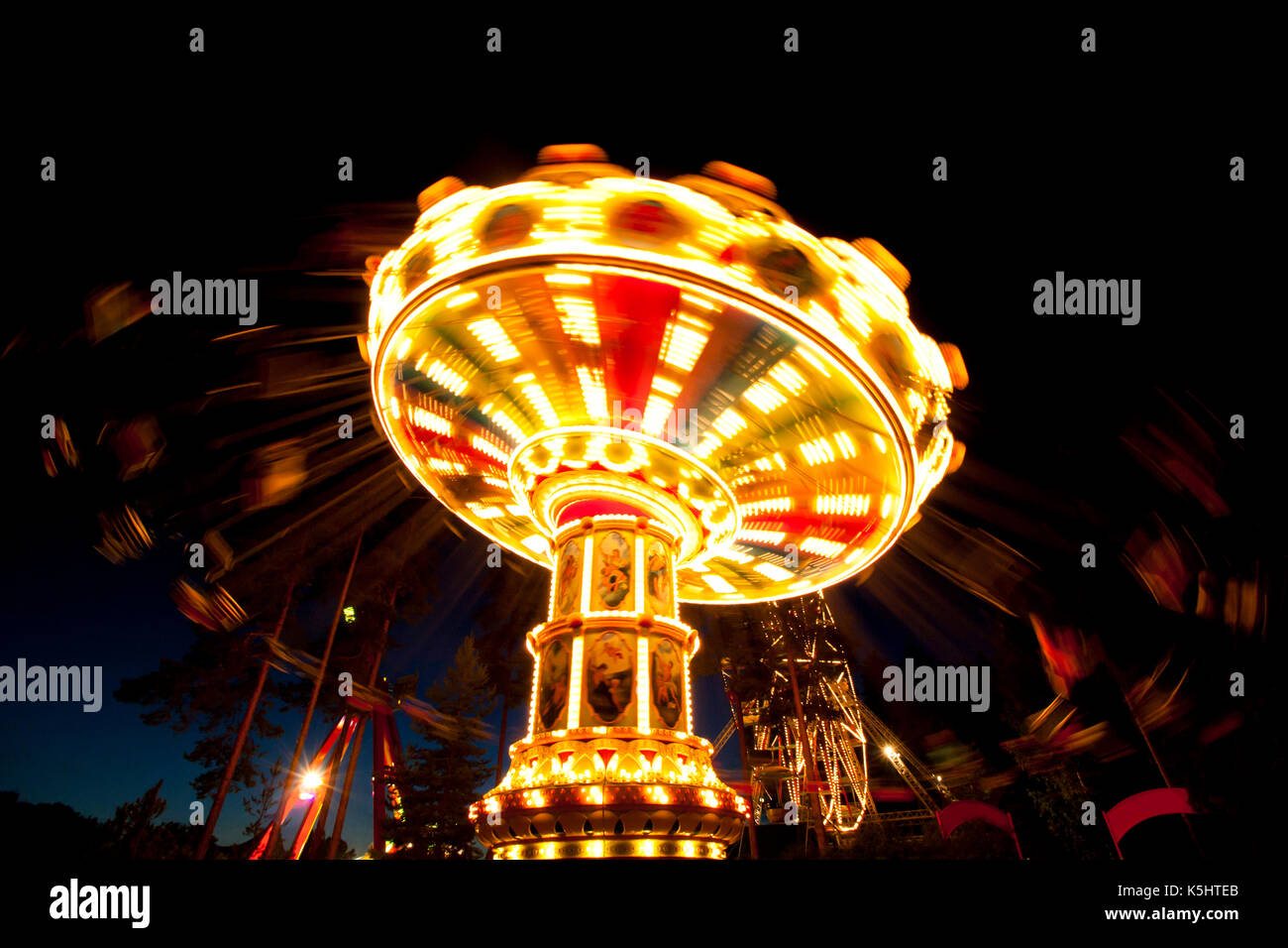 Colorful chain swing carousel in motion at amusement park at night ...