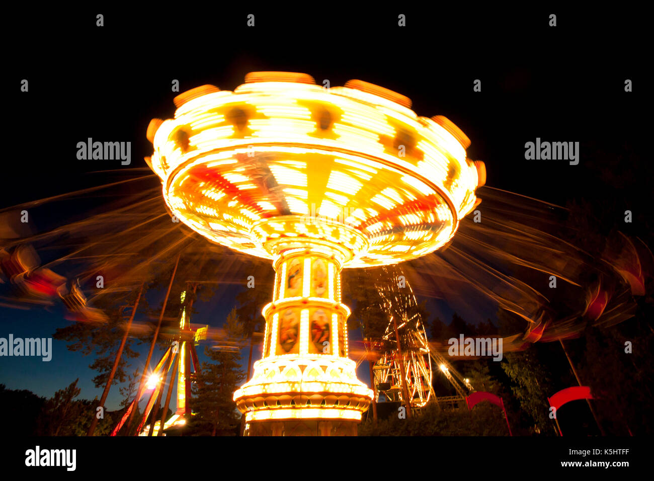 Colorful chain swing carousel in motion at amusement park at night ...