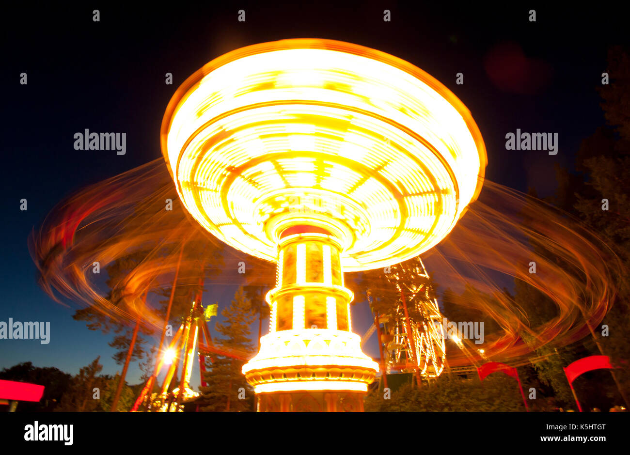 Colorful chain swing carousel in motion at amusement park at night ...