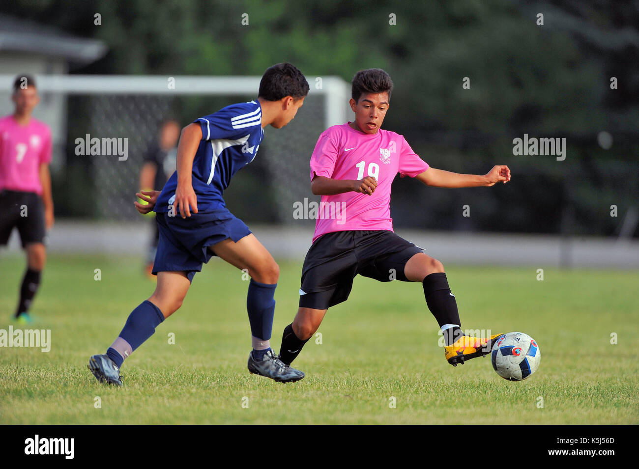 Forward striving to control the ball while being pressured by a ...