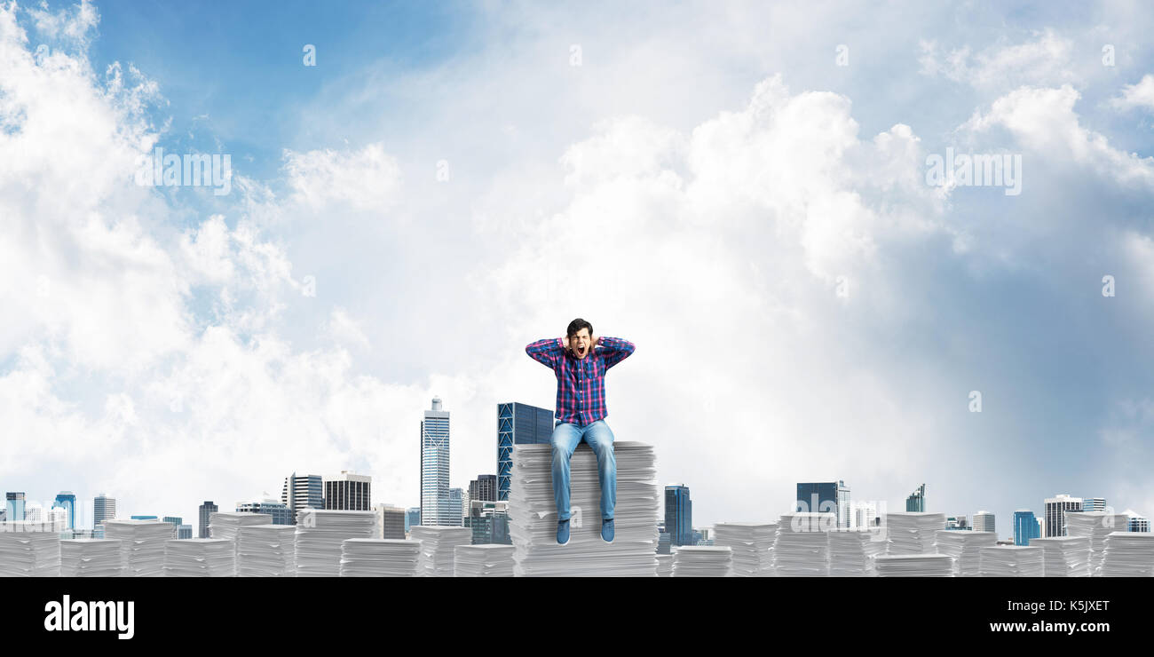 Attractive man sitting on pile of paper documents Stock Photo - Alamy