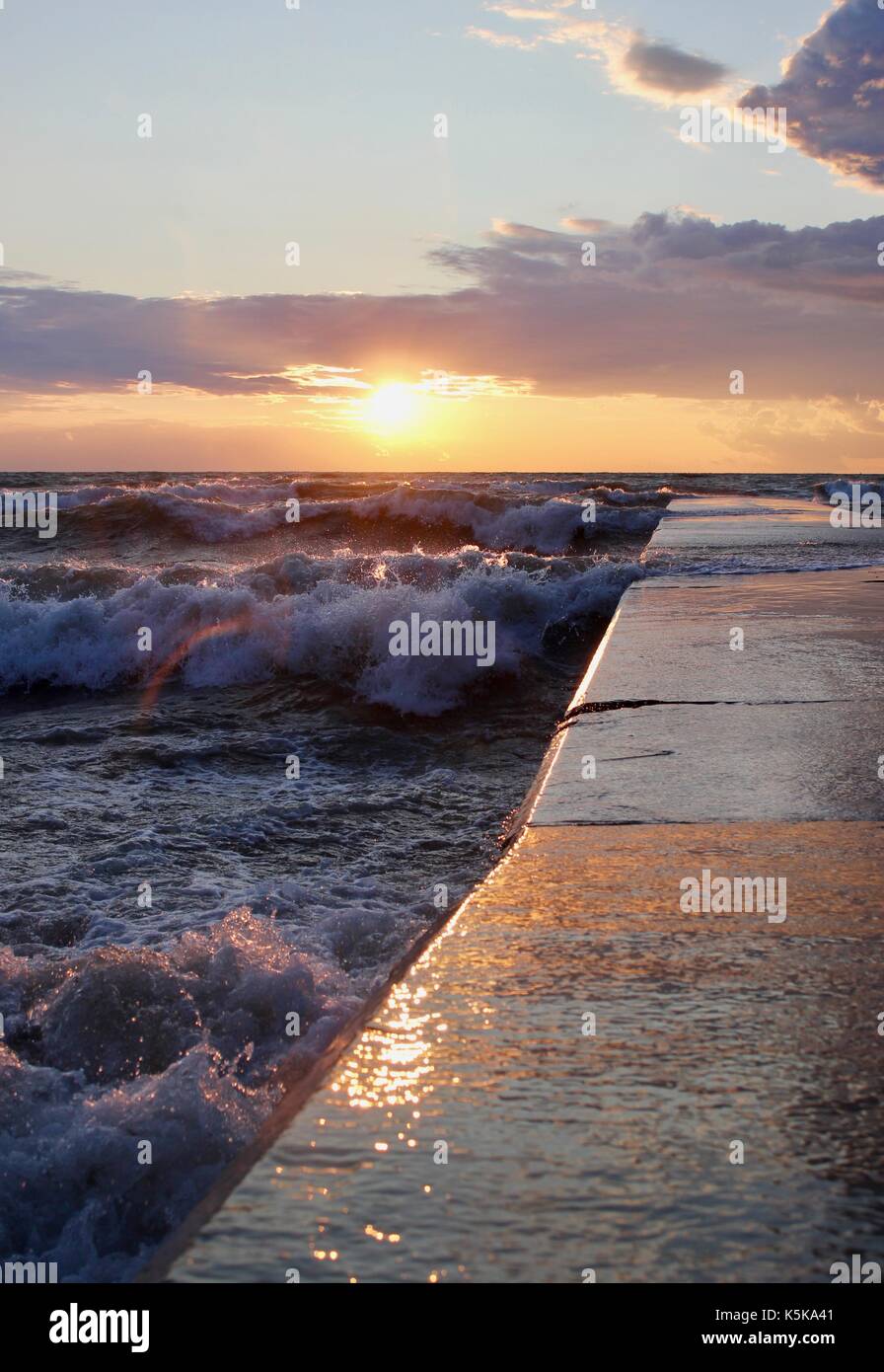 Lake Ontario's waves rolling over a pier, reflecting the beautiful ...
