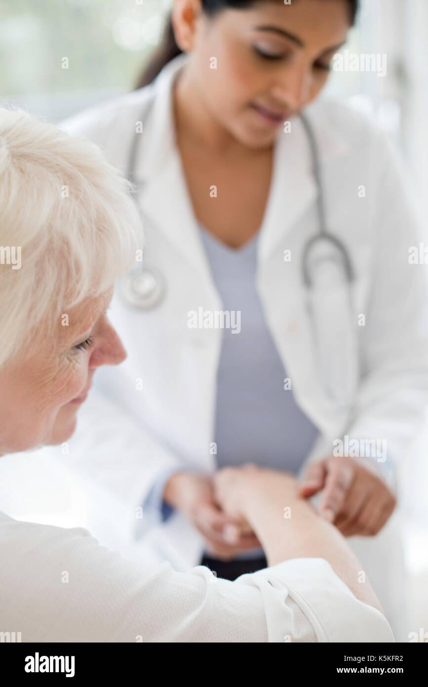 Female doctor examining patient's arm Stock Photo - Alamy