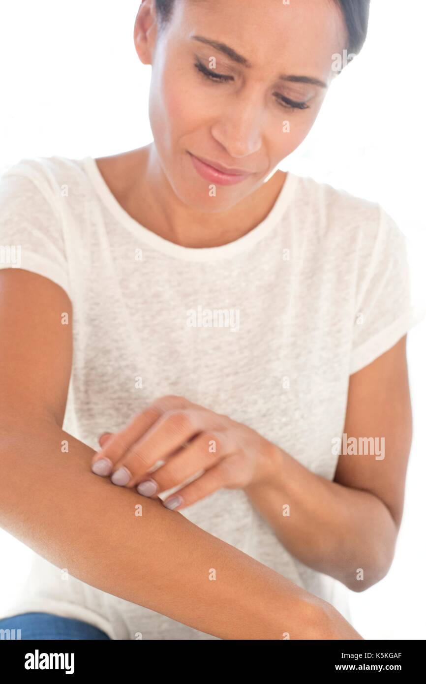Mid adult woman scratching arm Stock Photo - Alamy
