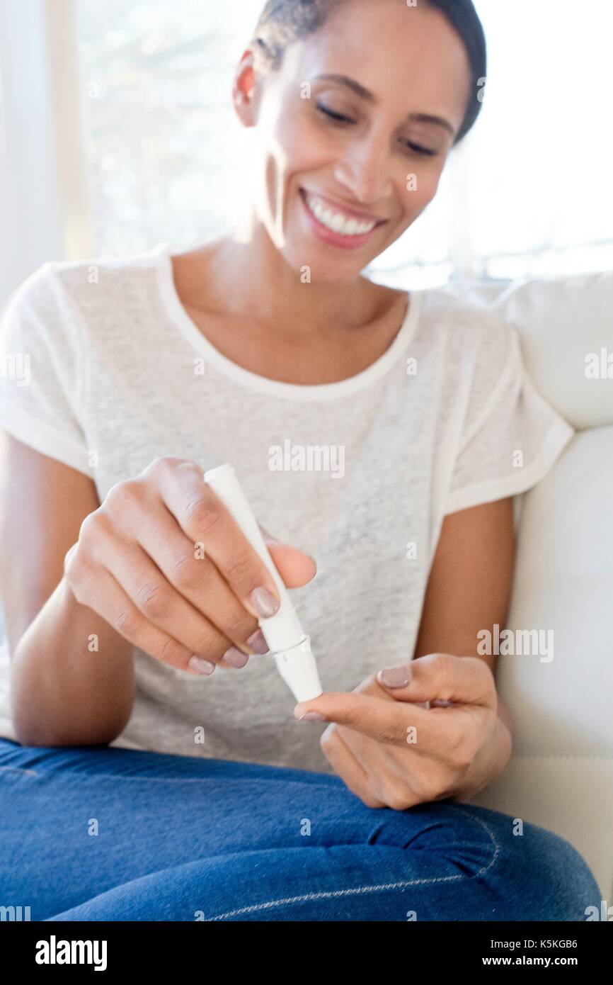 Mid adult woman doing pin prick test on finger Stock Photo - Alamy