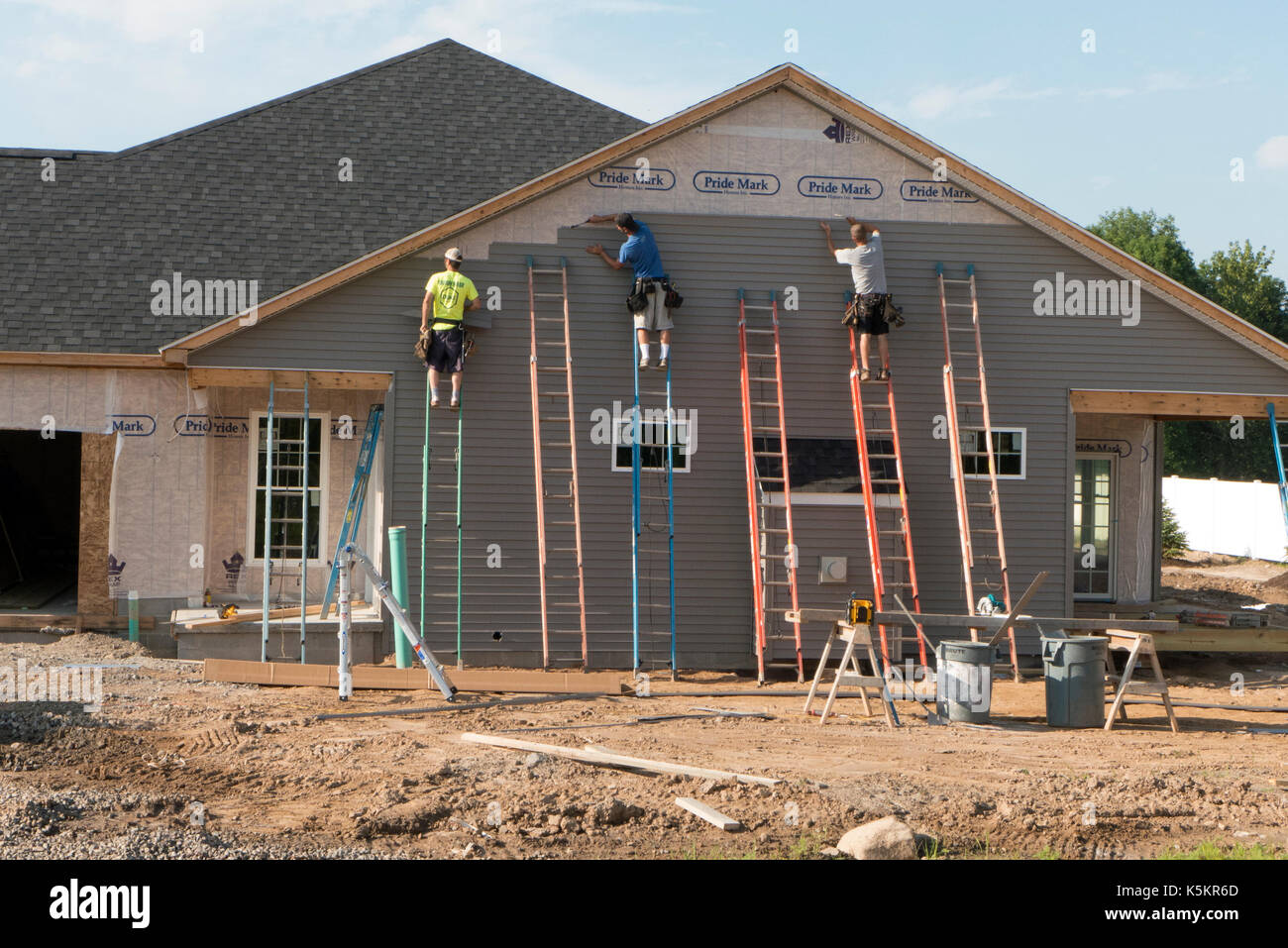 Teamwork, putting siding on building Stock Photo - Alamy