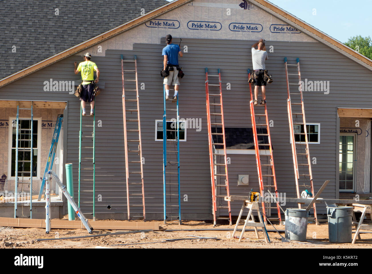 Teamwork, putting siding on building Stock Photo - Alamy