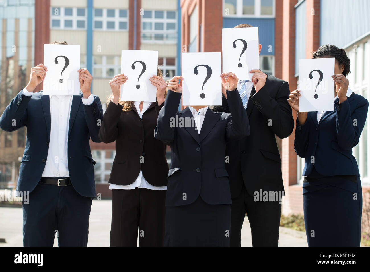 Group Of Businesspeople Hiding Face Behind Question Mark Sign;Outdoor ...
