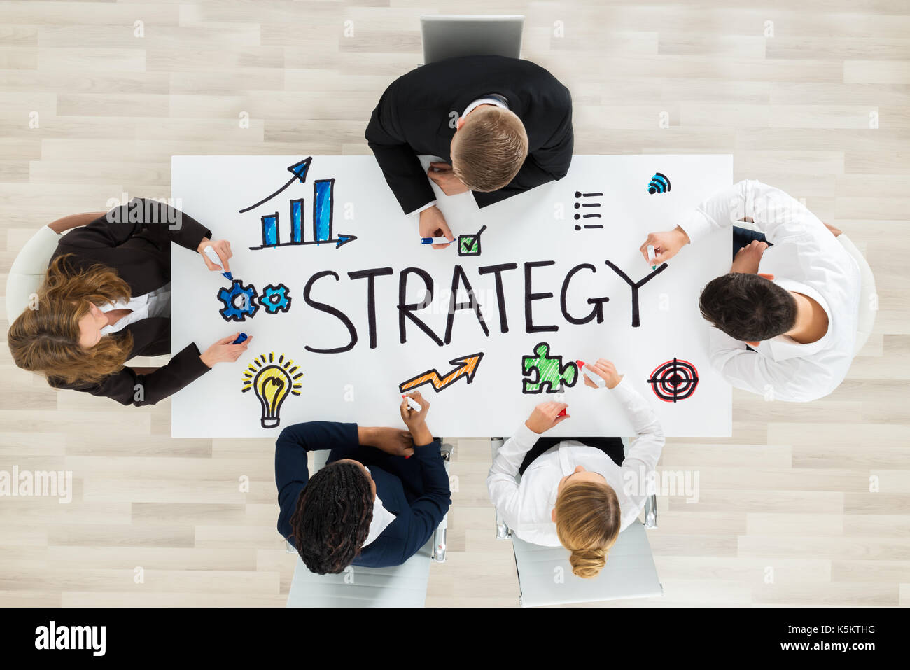 Team Of Professional Businesspeople Drawing Strategy Diagram With ...