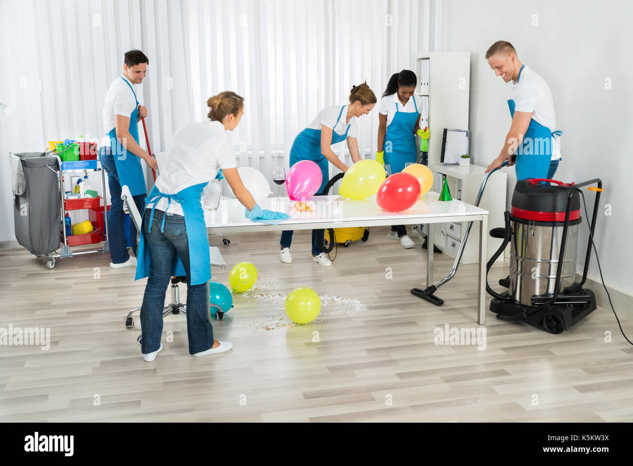 Group Of Male And Female Janitors Cleaning The Office After Party Stock ...