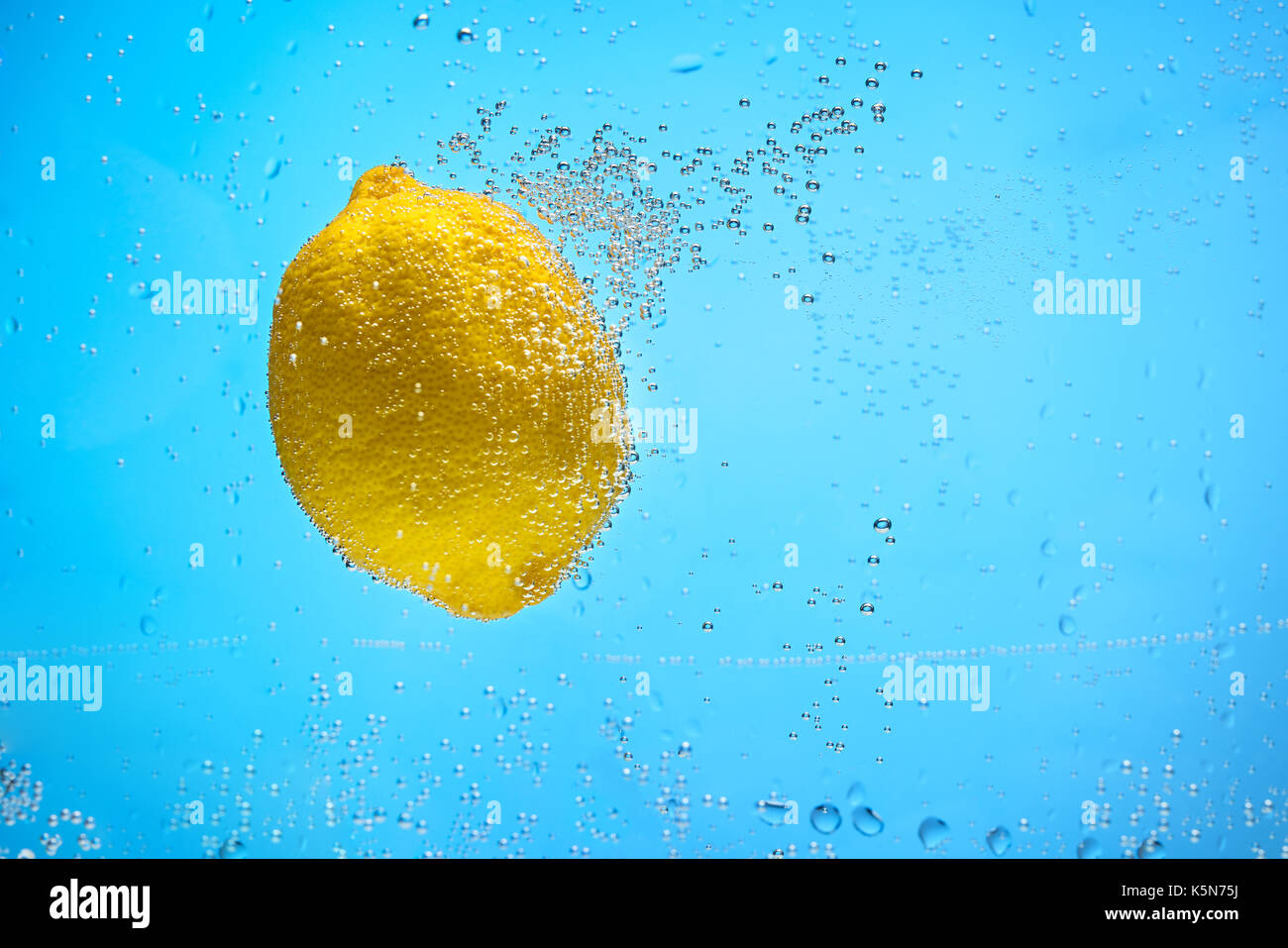 Single lemon floating in blue water Stock Photo - Alamy