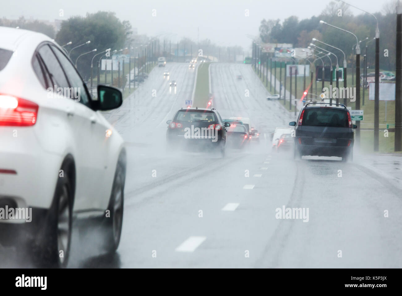 view wet road during the rain with cars riding through rain puddles ...