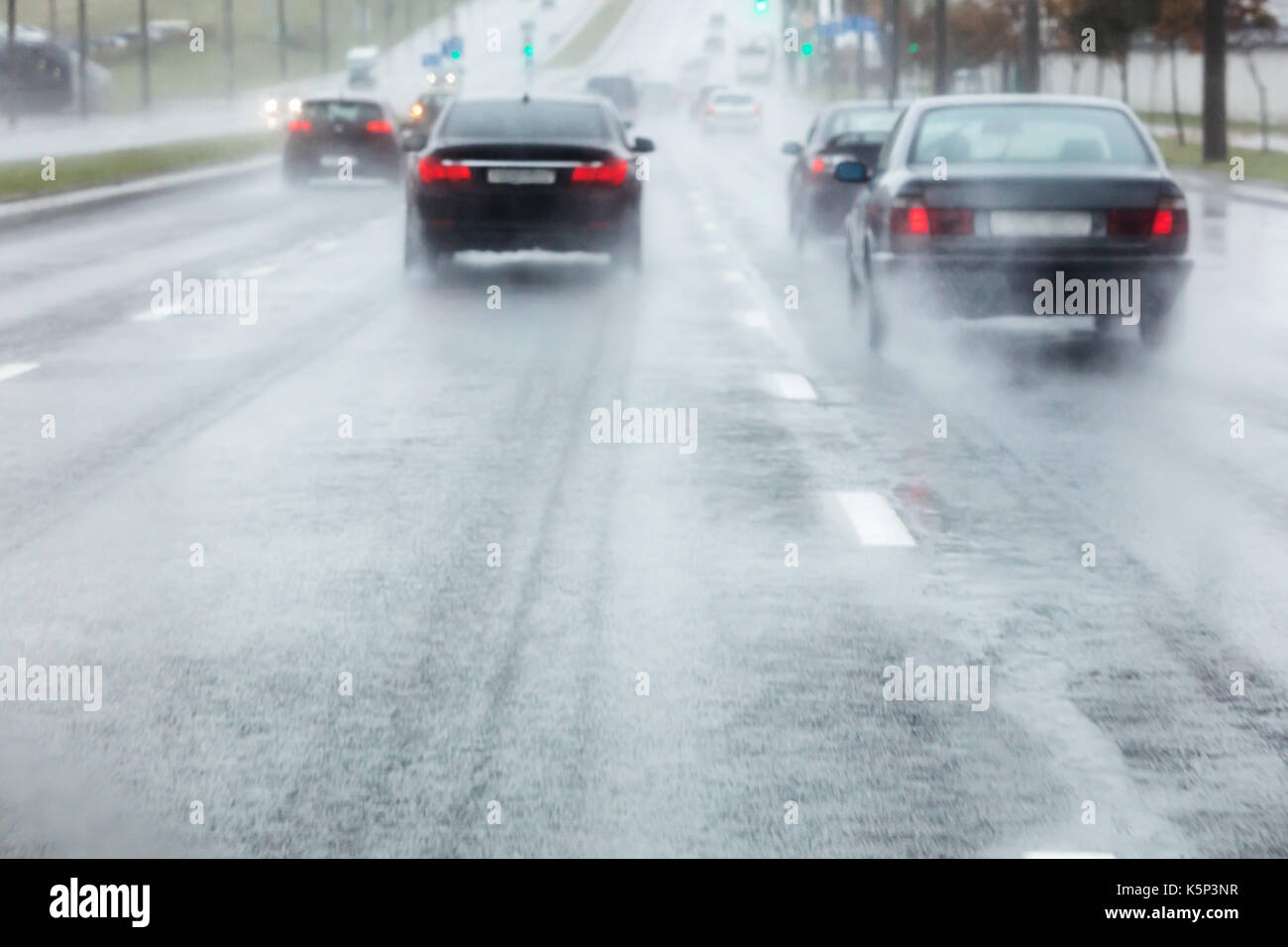 cars moving in wet road with water spraying from the wheels. blurred ...