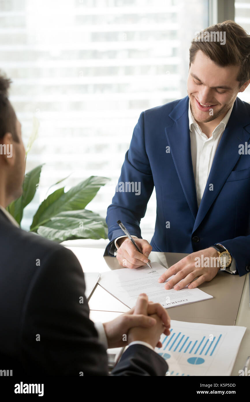 Happy entrepreneur signing contract with partner Stock Photo - Alamy