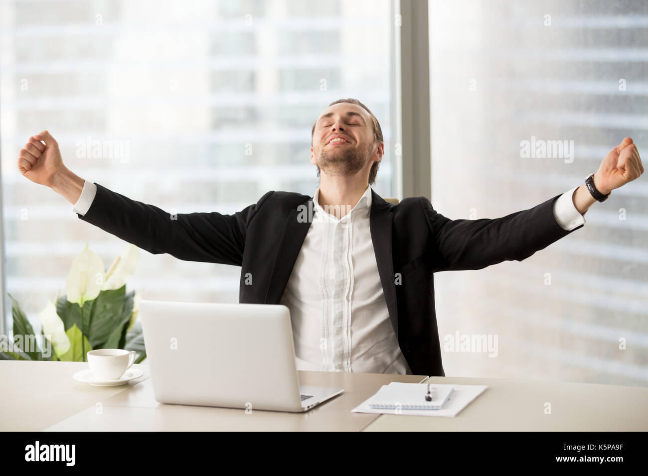 Smiling happy businessman celebrating finished work project at Stock ...
