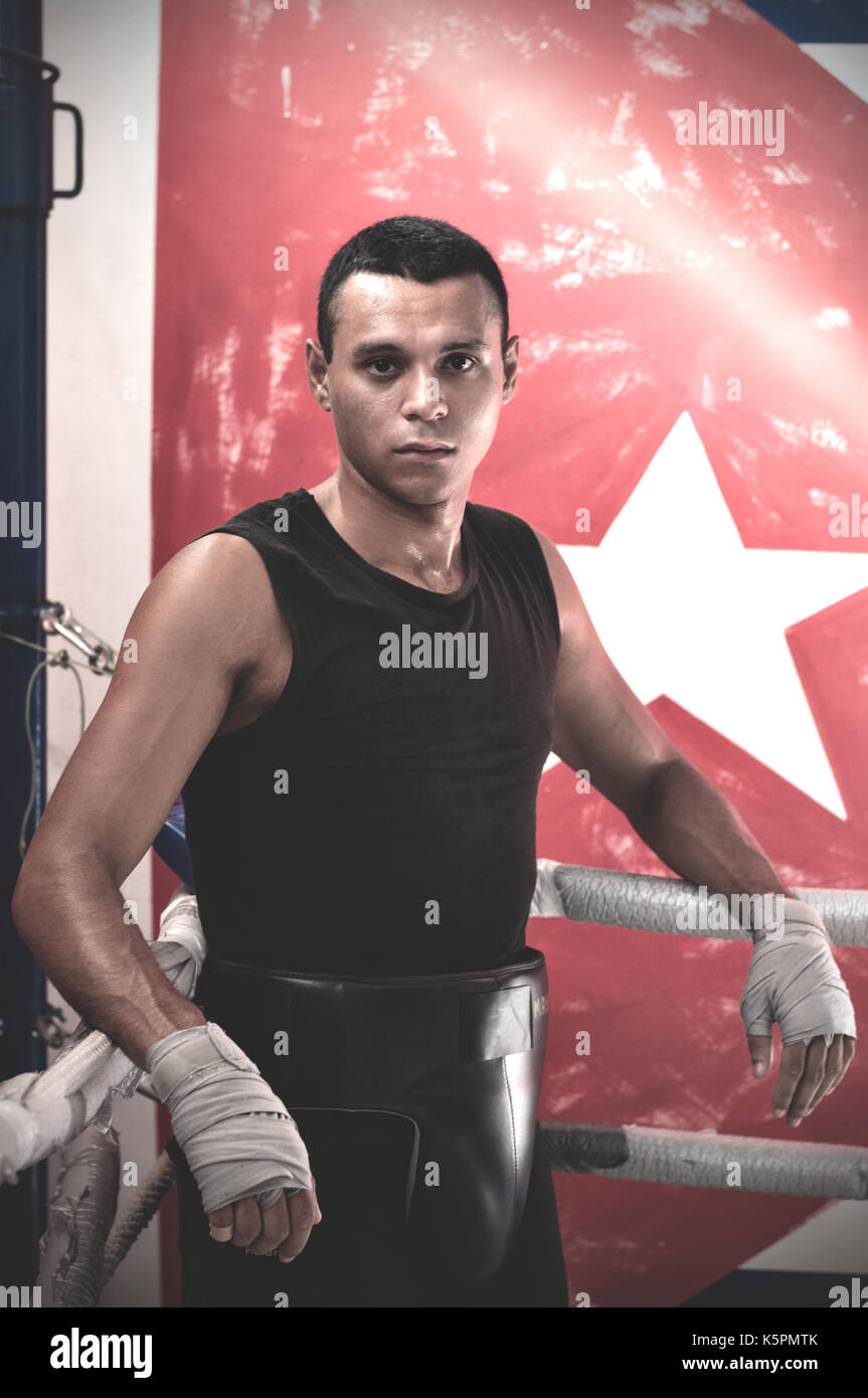 Portrait of sweaty latin american male boxer leaning on ropes on a ...