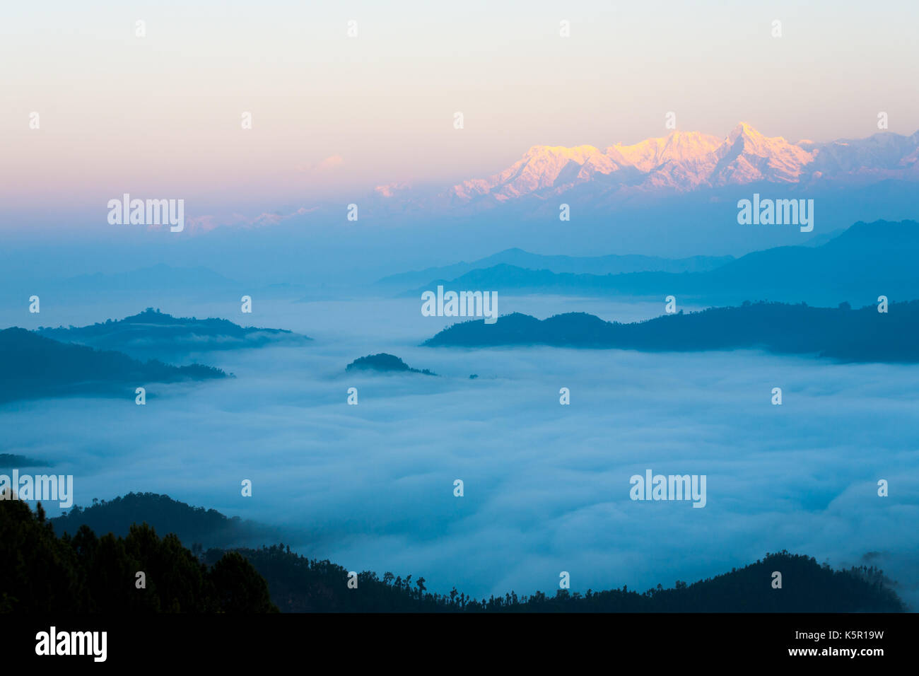 Tops of distant Himalayan mountain peaks glow red from morning sunrise ...