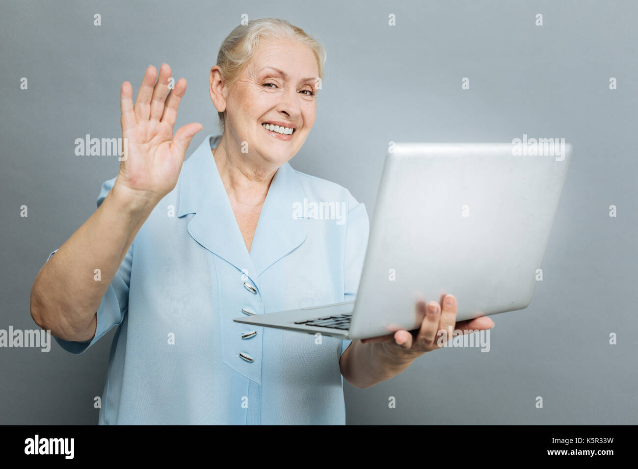Positive mature female waving her right hand Stock Photo - Alamy