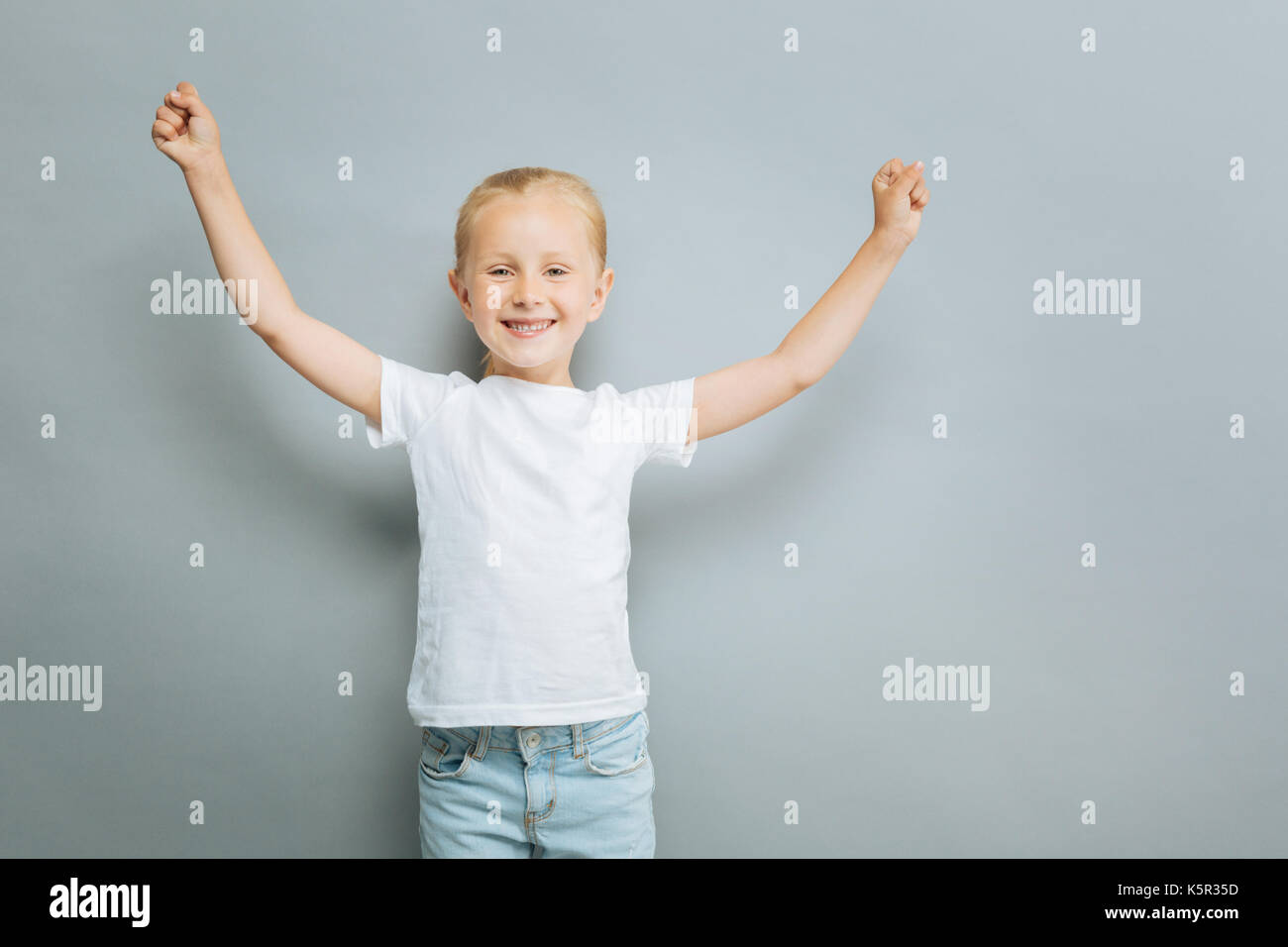 Delighted kid raising her arms up Stock Photo - Alamy