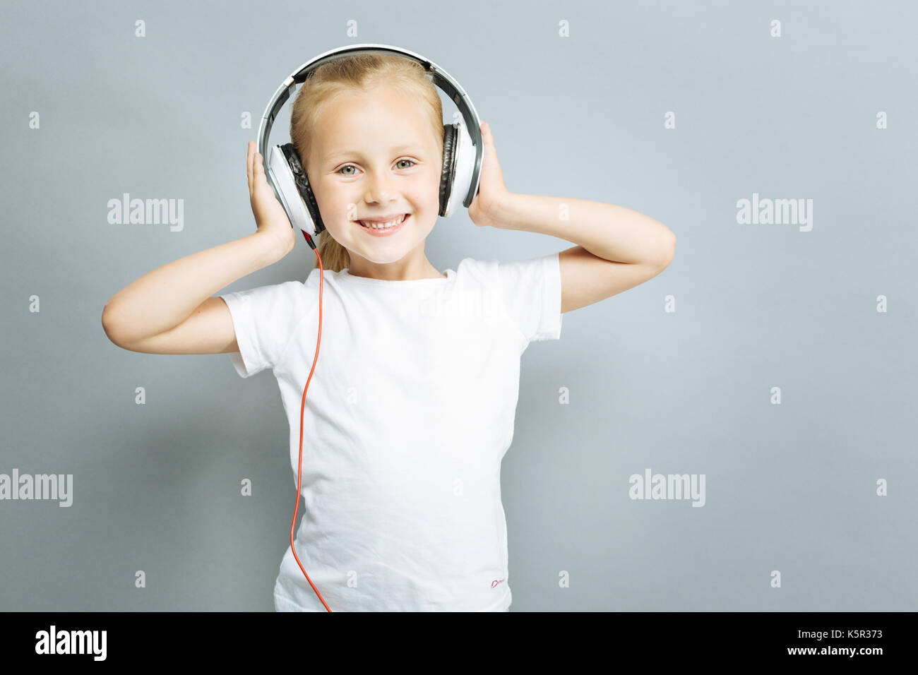 Positive delighted child touching her headphones Stock Photo - Alamy