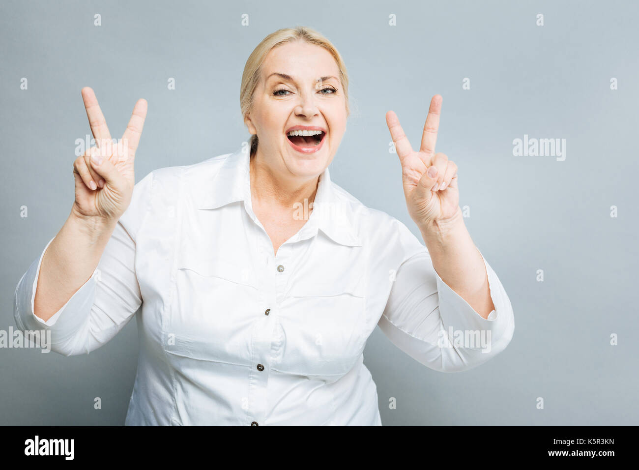 Happy female person showing victory sign Stock Photo - Alamy
