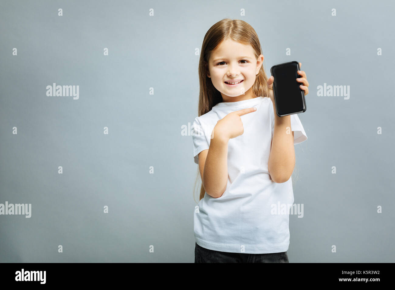 Cheerful kid pointing at her telephone Stock Photo - Alamy