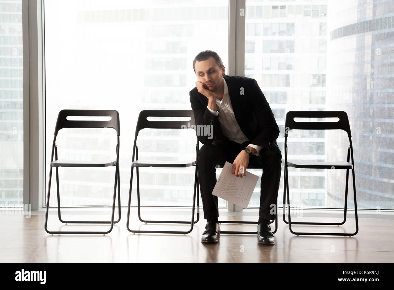 Bored young man in suit sitting in waiting room Stock Photo - Alamy