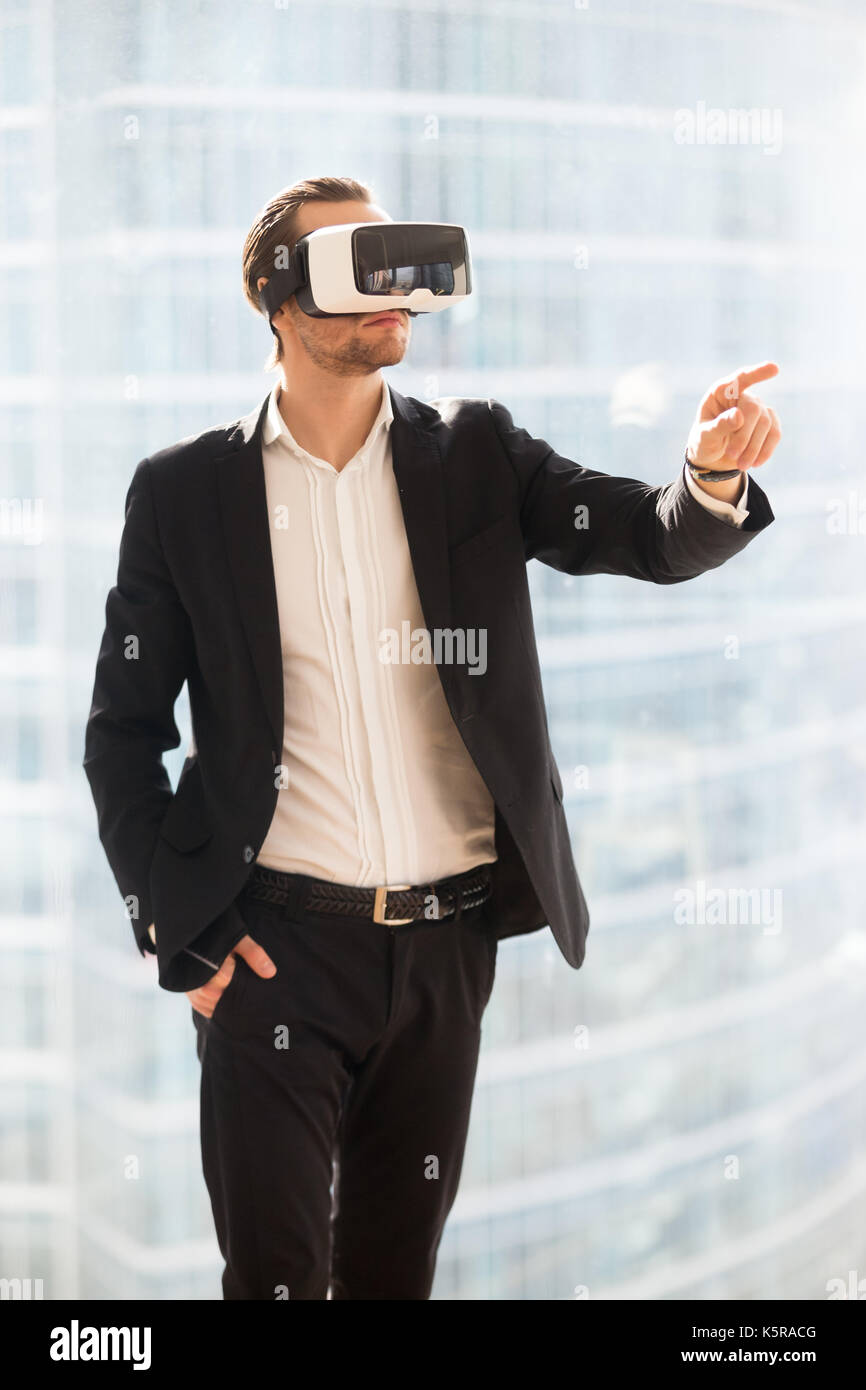 Businessman in VR glasses pointing finger in the air Stock Photo - Alamy