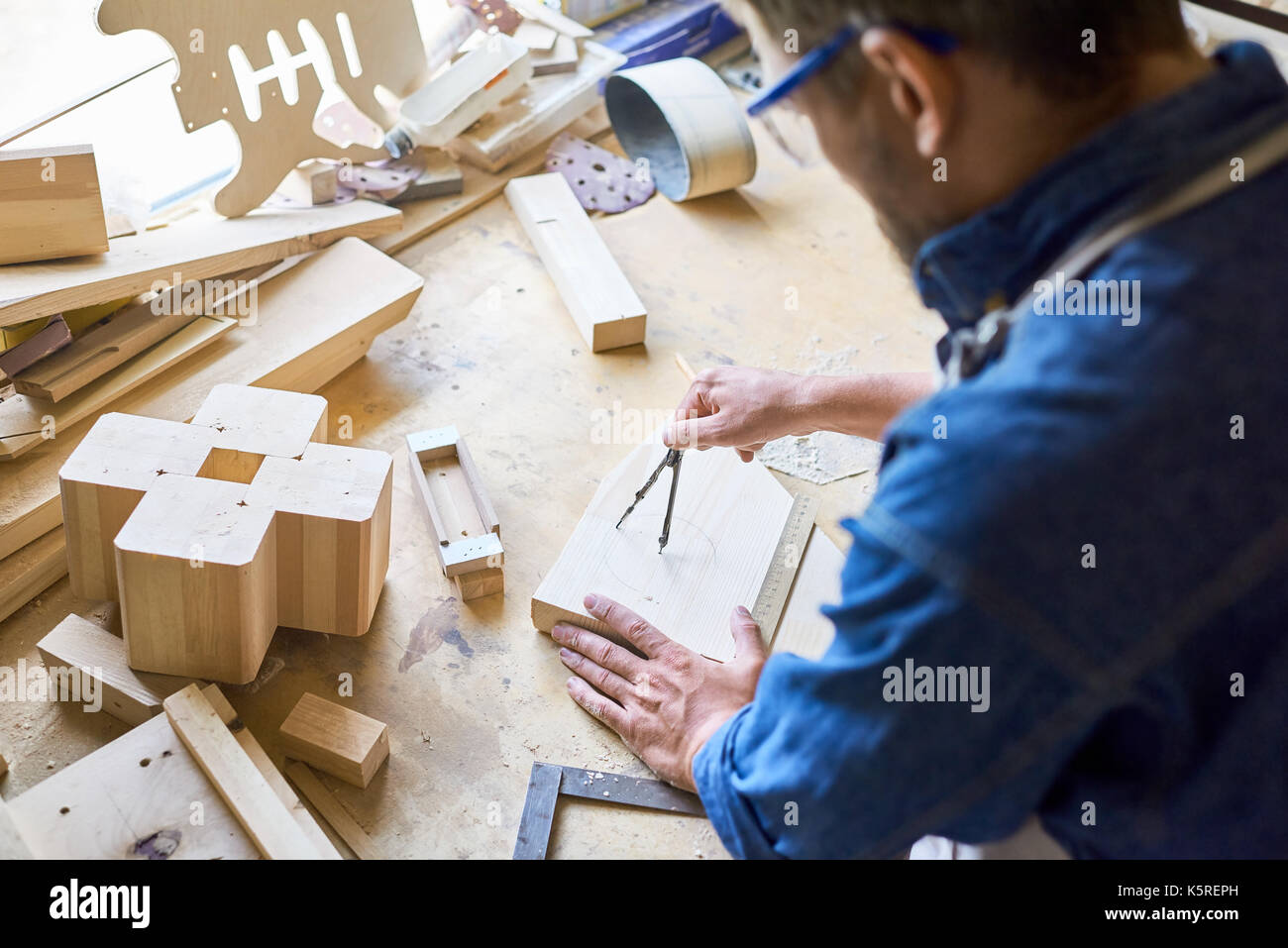 Over shoulder view of experienced carpenter using compass in order to ...