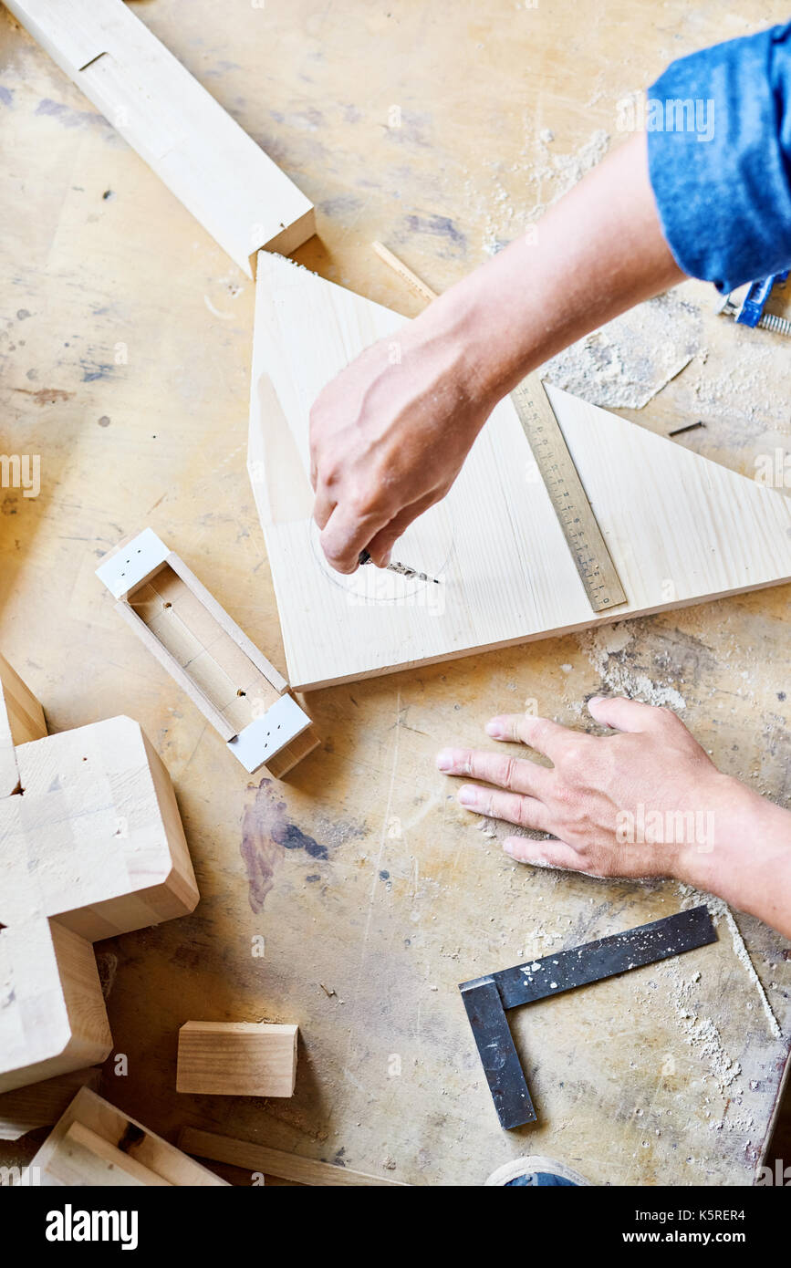 Directly above view of unrecognizable carpenter using compass to draw ...