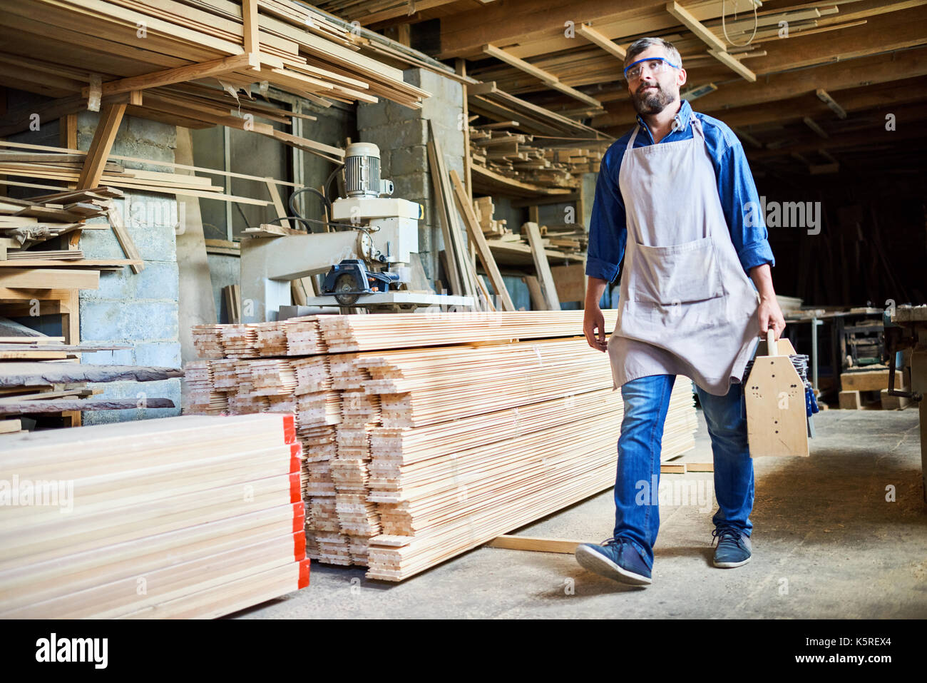 Full length portrait of confident bearded carpenter wearing apron and ...