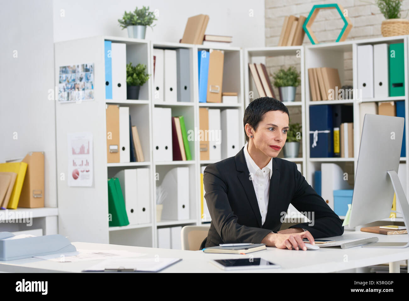 Hard-working pretty manager sitting in front of computer and analyzing ...
