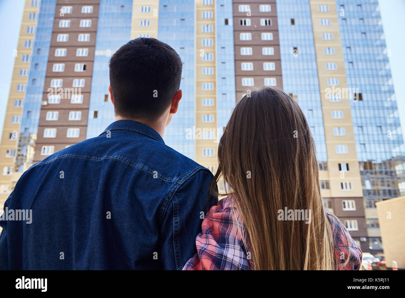 Back view portrait of young couple embracing looking at new apartment ...