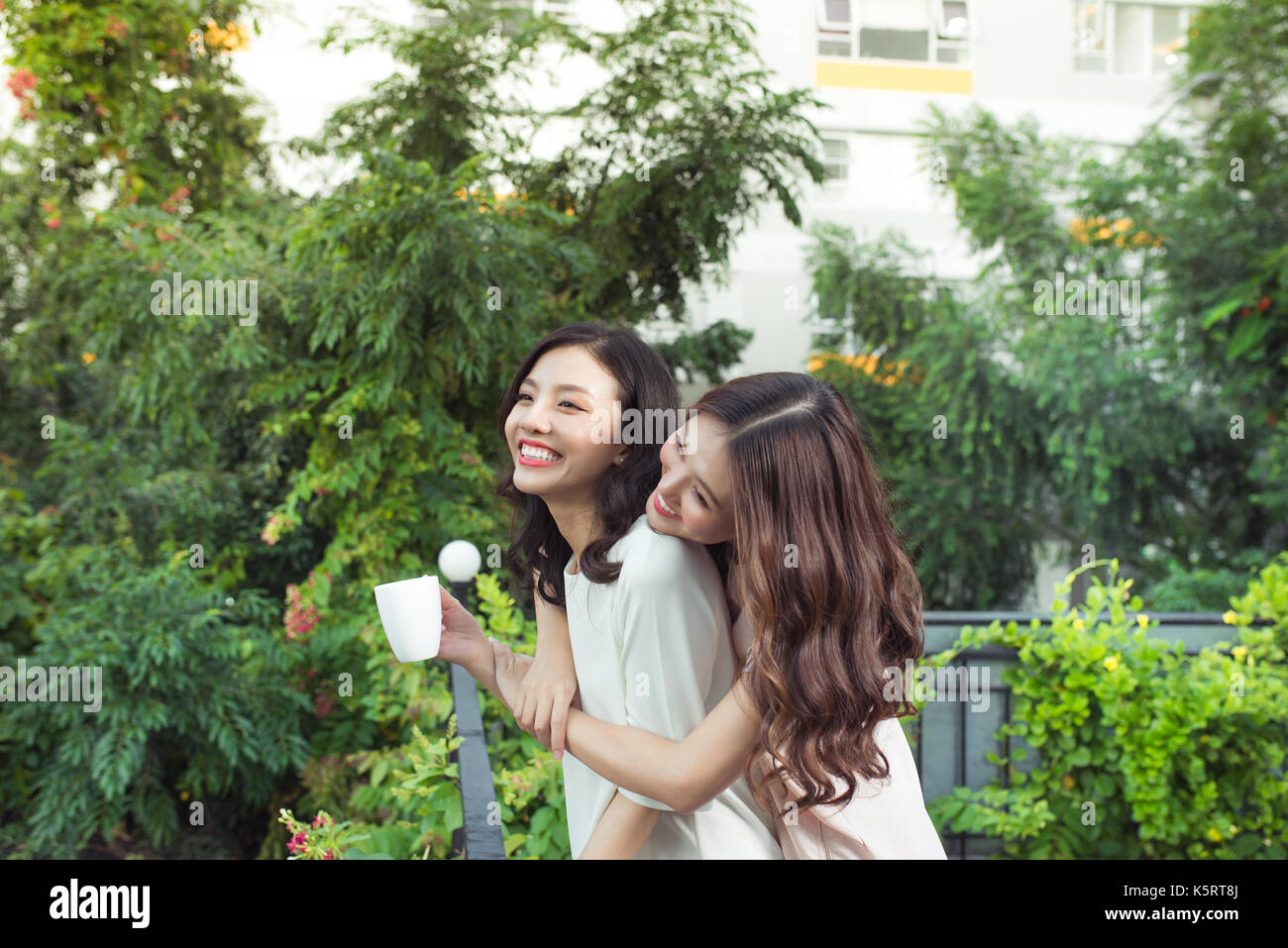 Happy young women friends well-dressed smiling while standing together ...