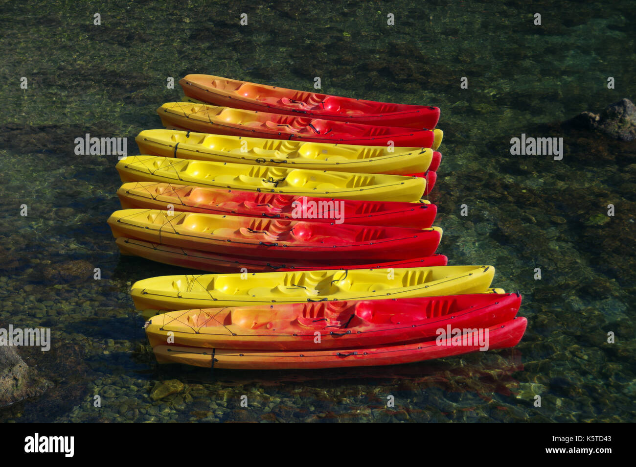 Colorful canoes on water. Red and yellow kayaks ready for summer ...