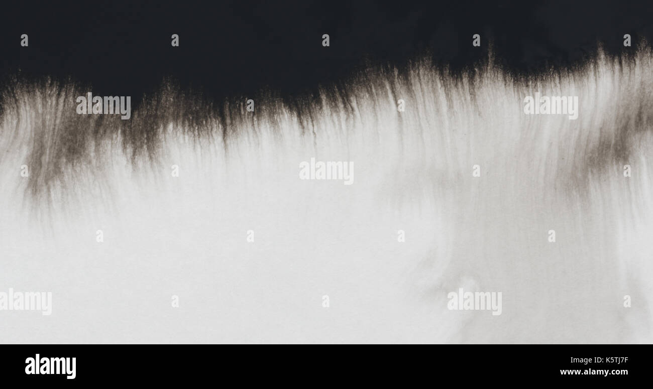 closeup black ink border spreading on wet paper top view, wide photo ...