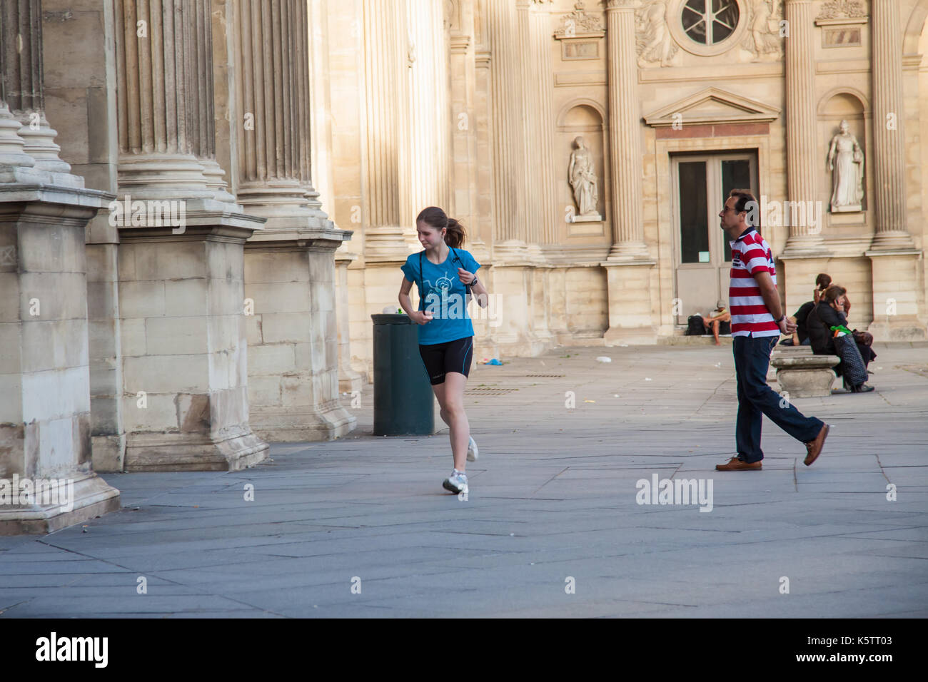 A young girl running along the walls of the Louvre Museum training for ...