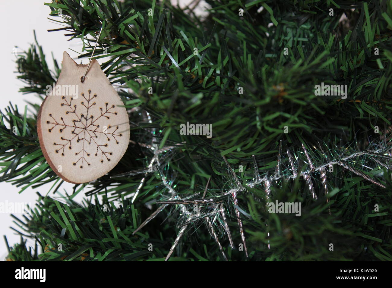 Handmade pyrography snowflake ornament on a Christmas tree with white ...