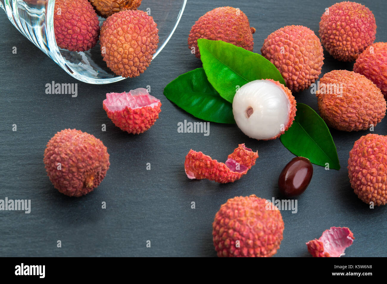 Fresh pile of lychees with leaves on black stone background Stock Photo ...