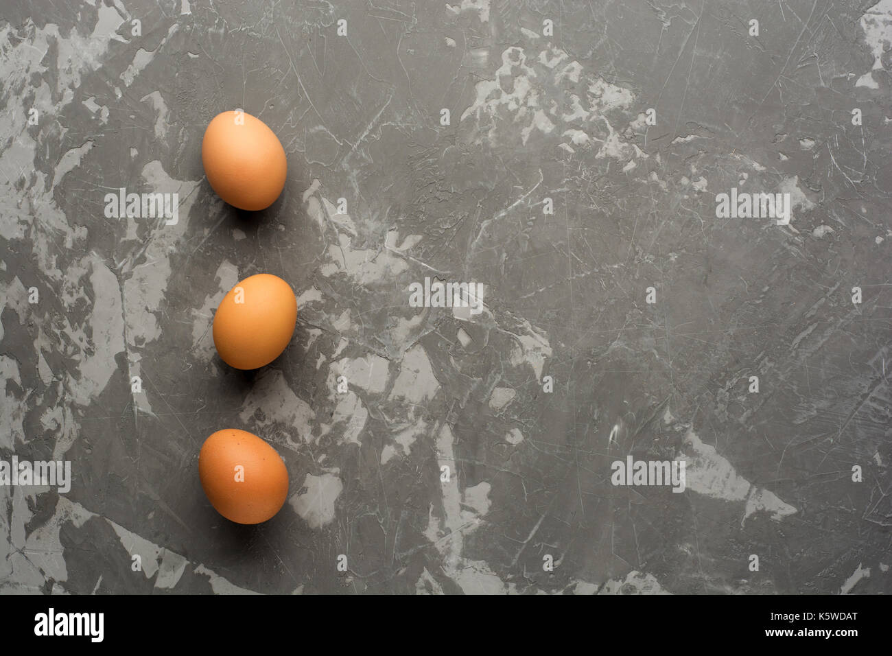 Three eggs on a concrete table. Top View Stock Photo - Alamy